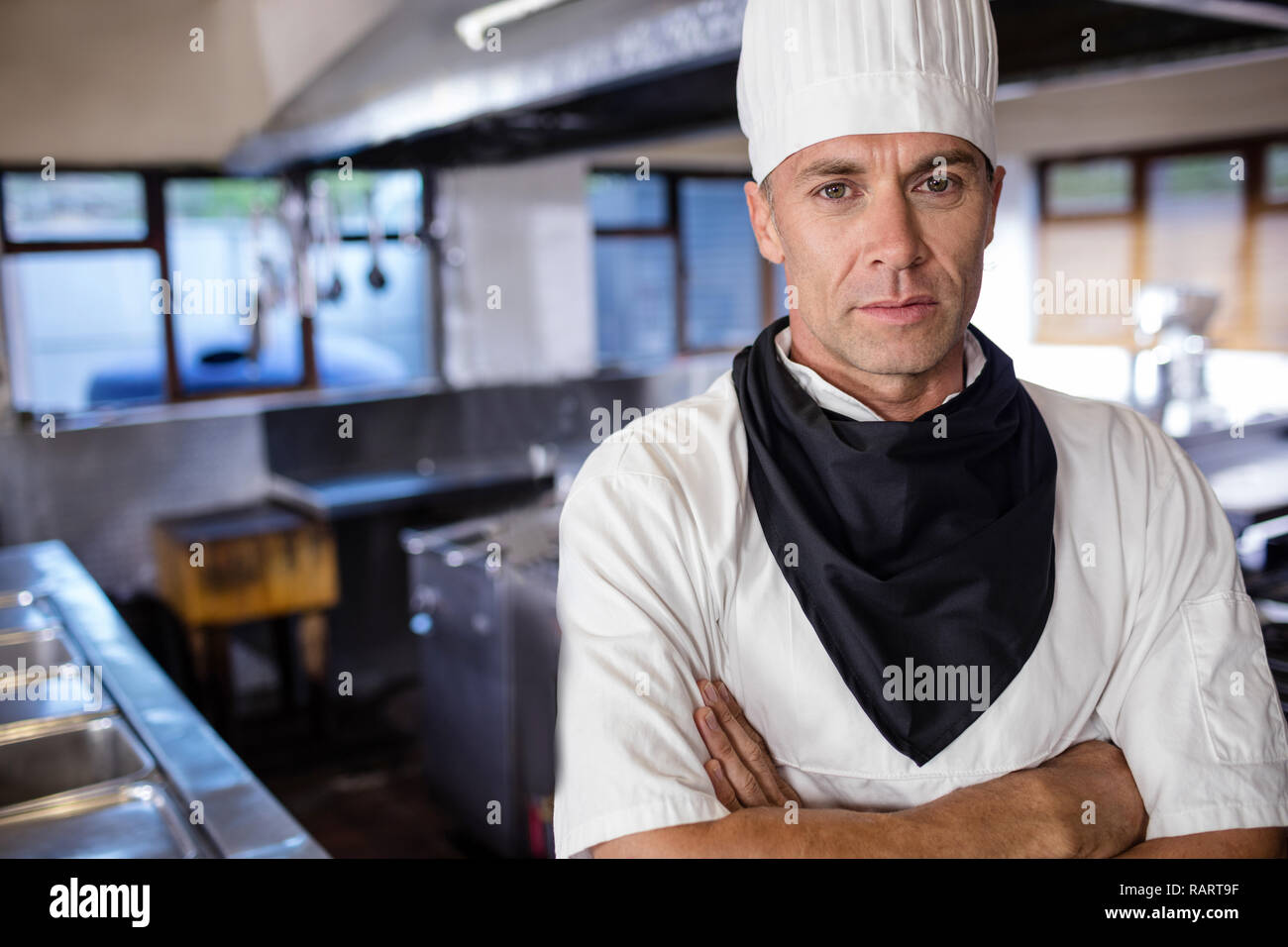 Male chef standing with arms crossed in kitchen Stock Photo - Alamy
