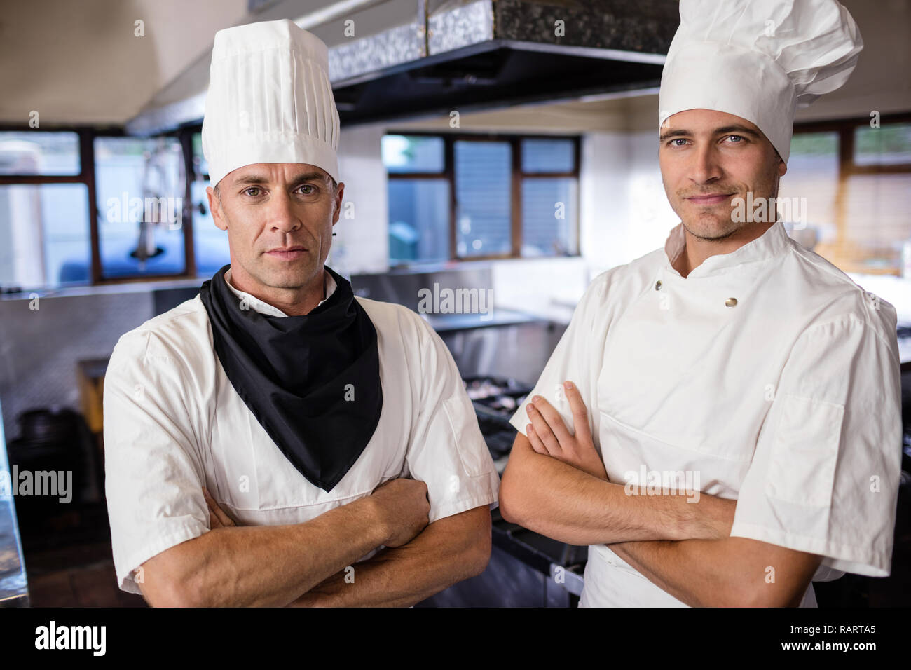 Two male chefs standing with arms crossed in kitchen Stock Photo - Alamy