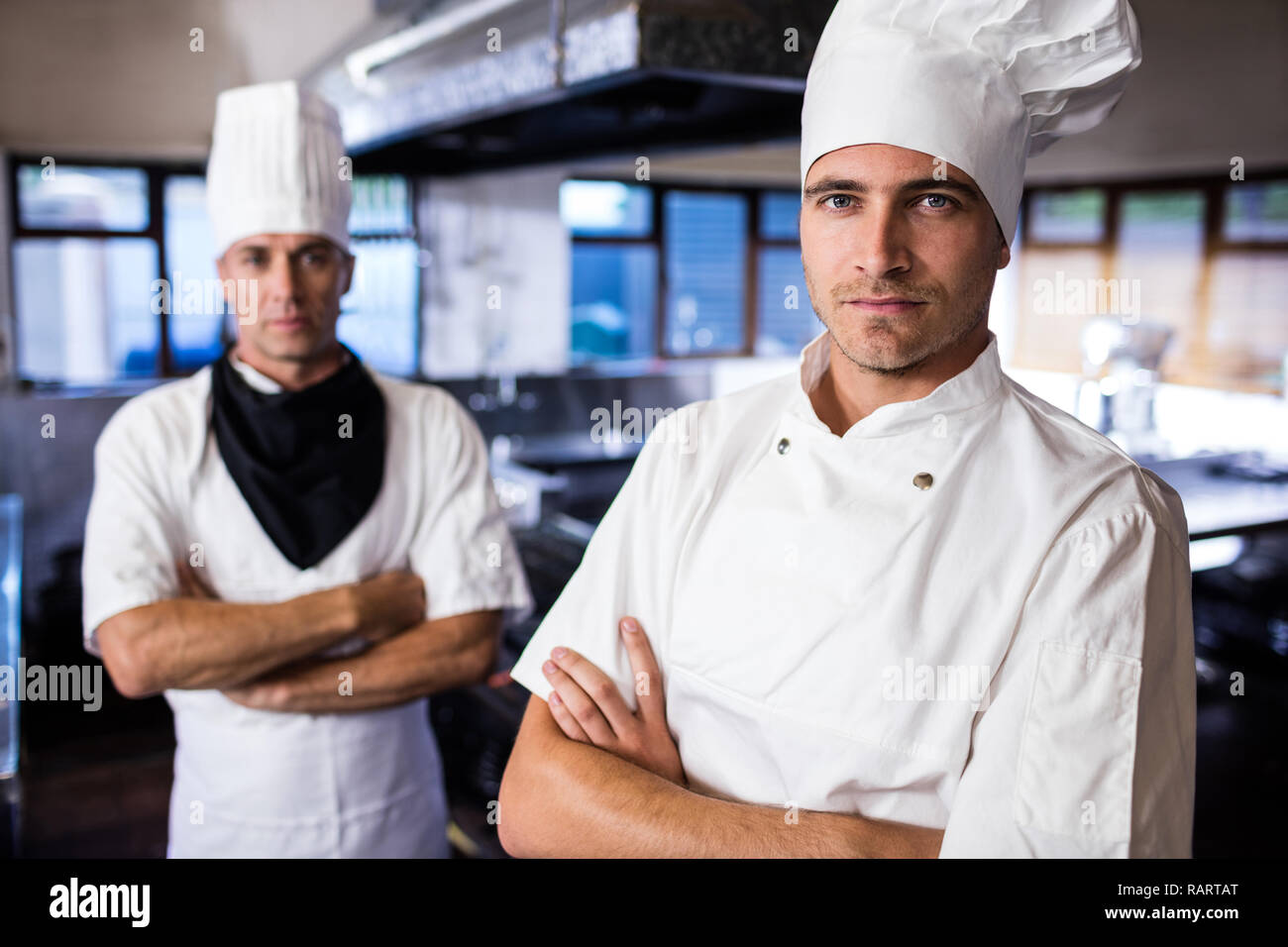 Two male chefs standing with arms crossed in kitchen Stock Photo - Alamy