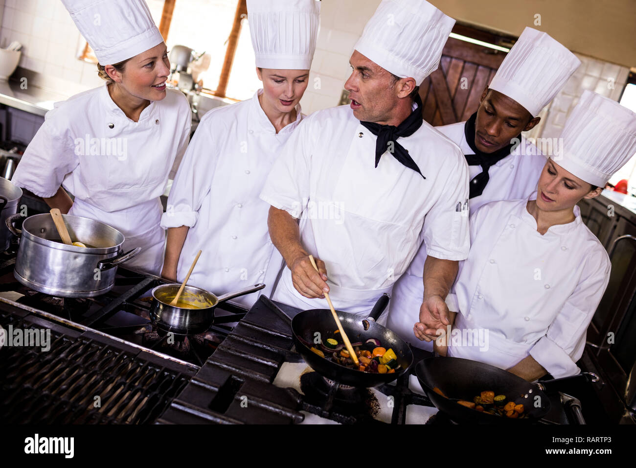 Group of chefs preparing food in kitchen Stock Photo - Alamy