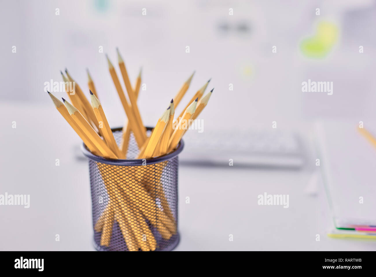 Graphite pencils in a metal grid-container on the office table. Concept ...