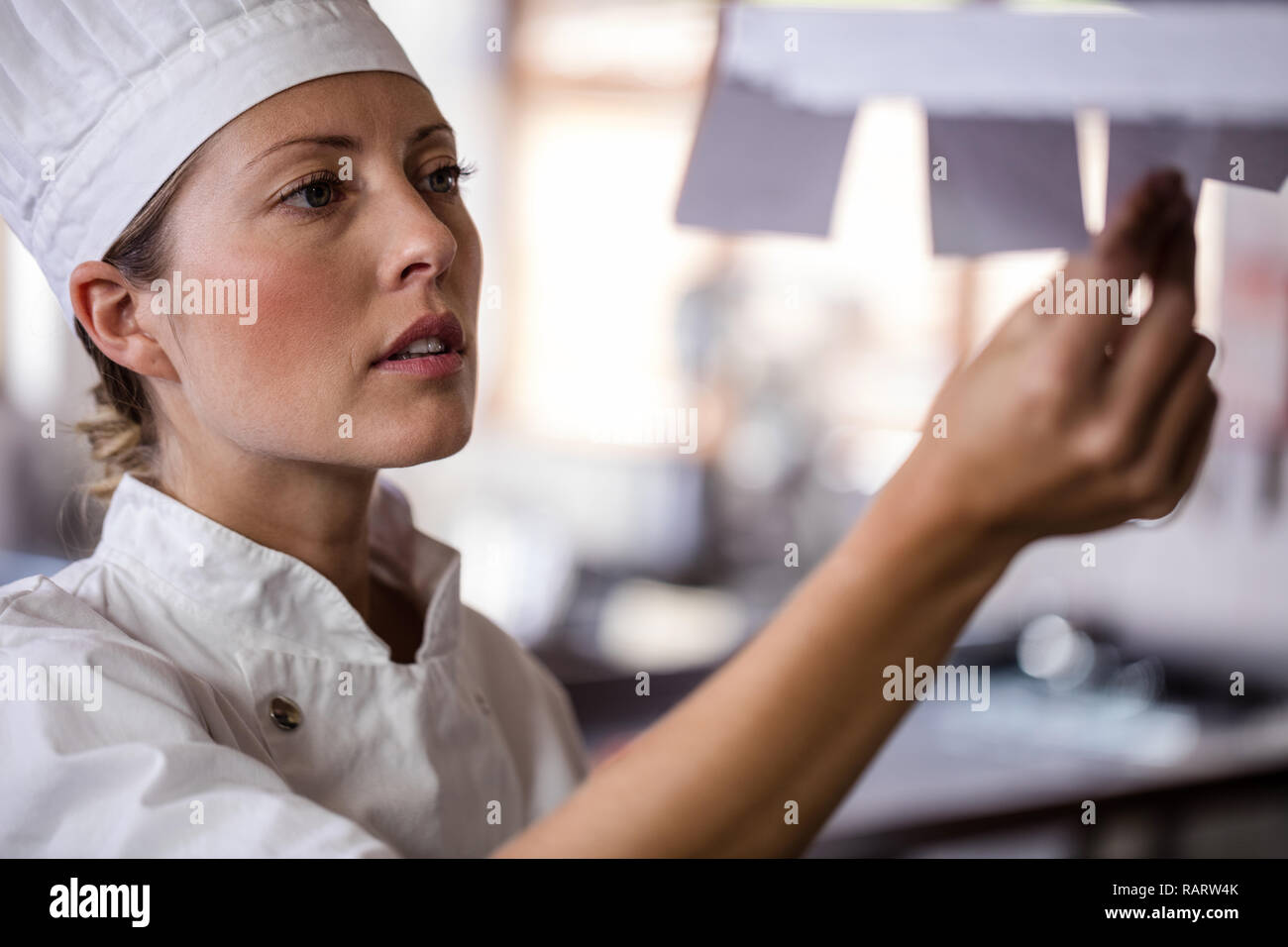 Female chef looking at order list in kitchen Stock Photo - Alamy