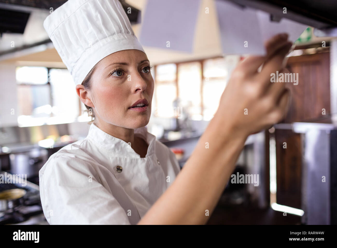 Female chef looking at order list in kitchen Stock Photo - Alamy