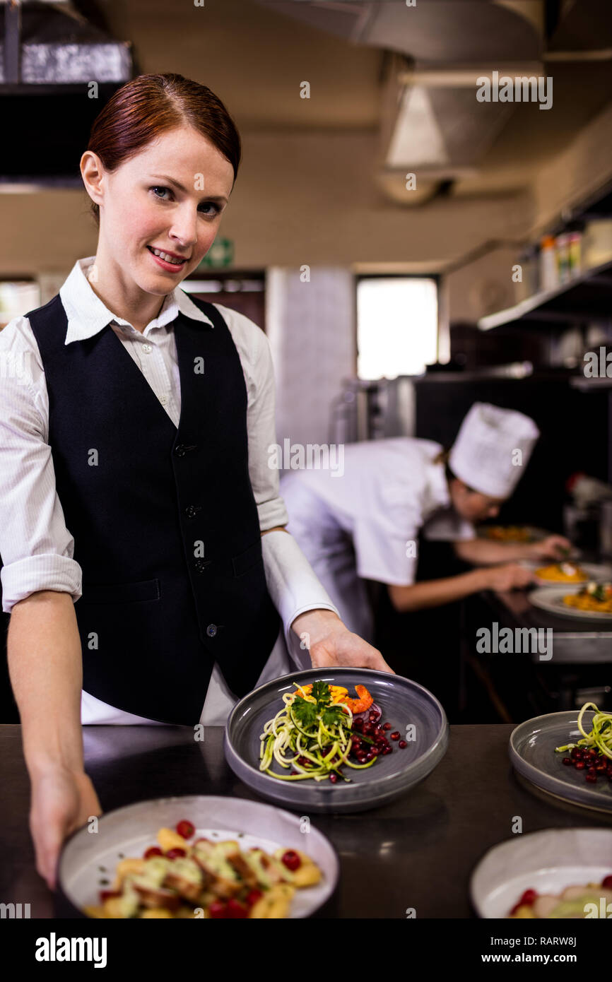 Female waitress holding plates with food in kitchen Stock Photo - Alamy