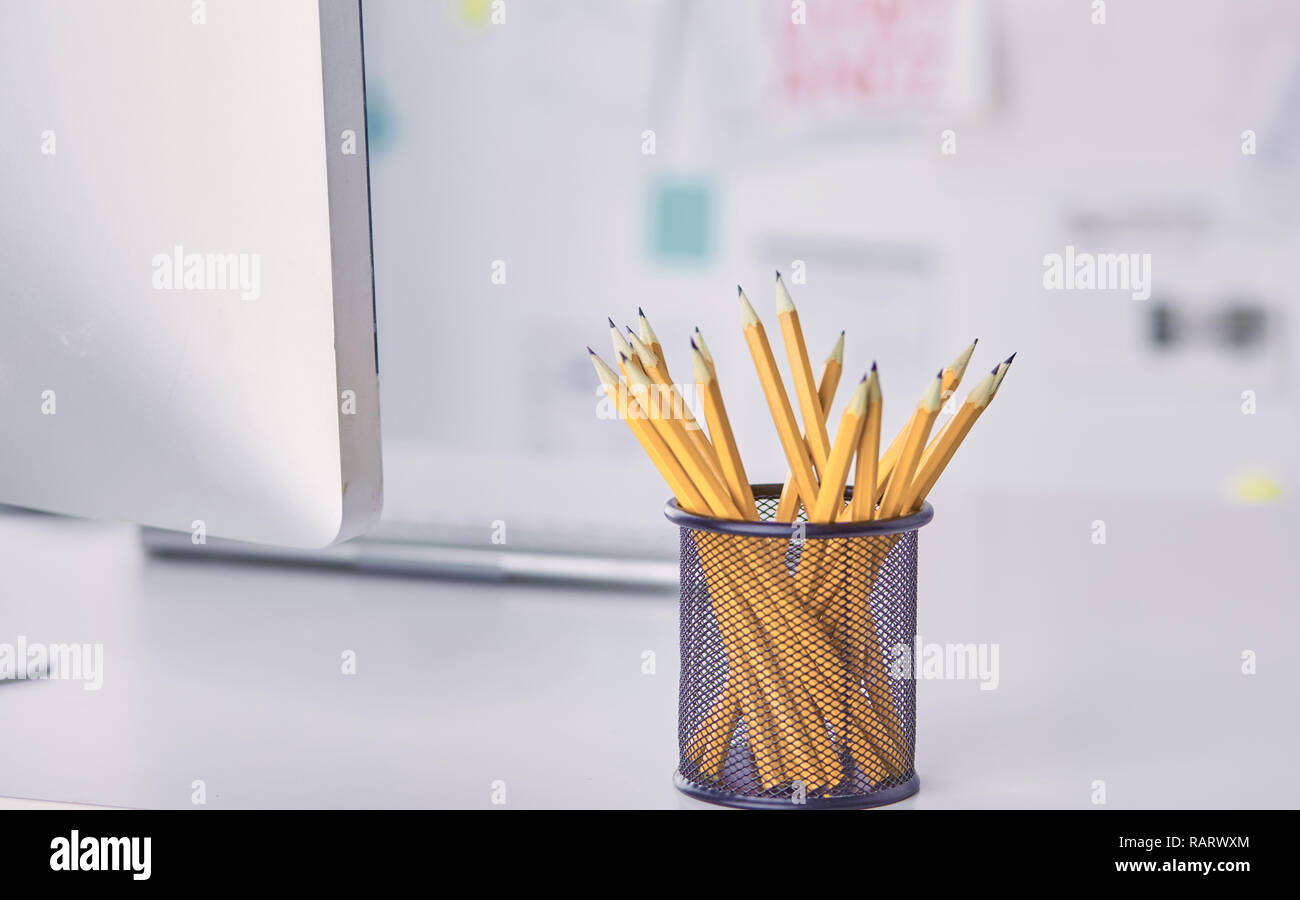 Graphite pencils in a metal grid-container on the office table. Concept ...