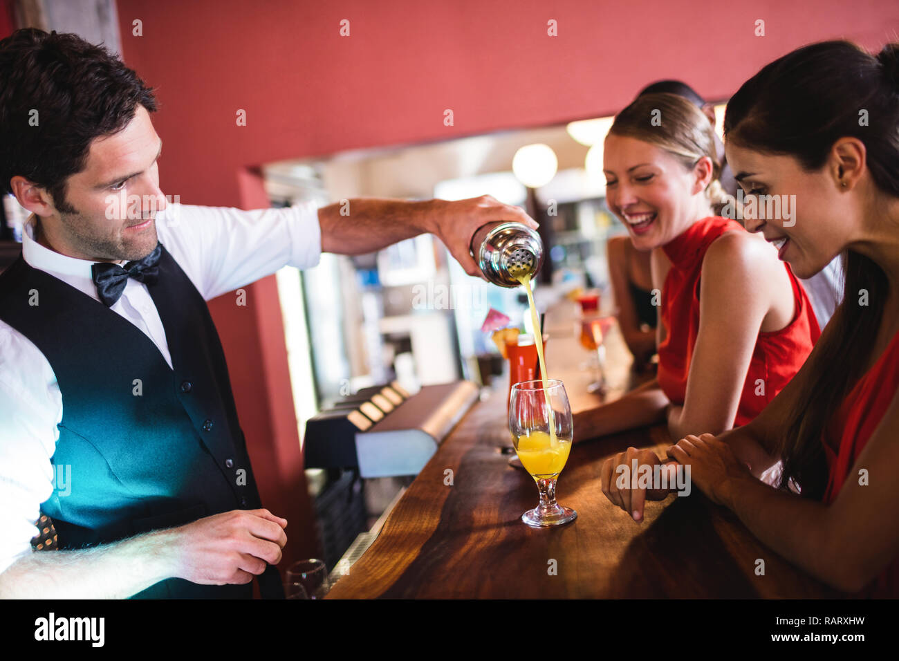 Bartender pouring cocktail in glass at bar counter Stock Photo - Alamy