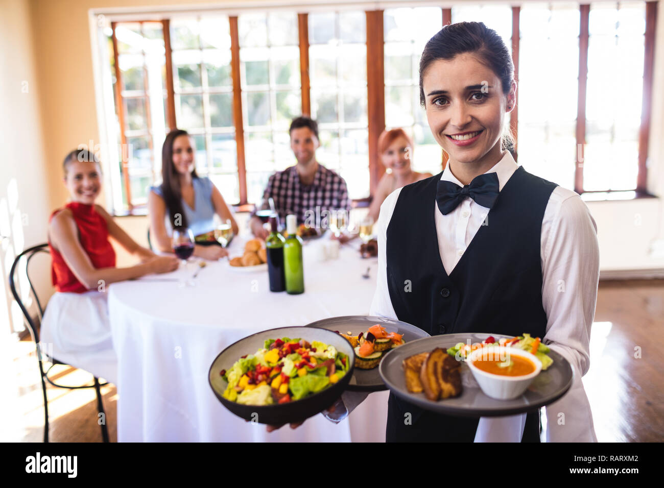 Waitress holding food on plate in restaurant Stock Photo - Alamy