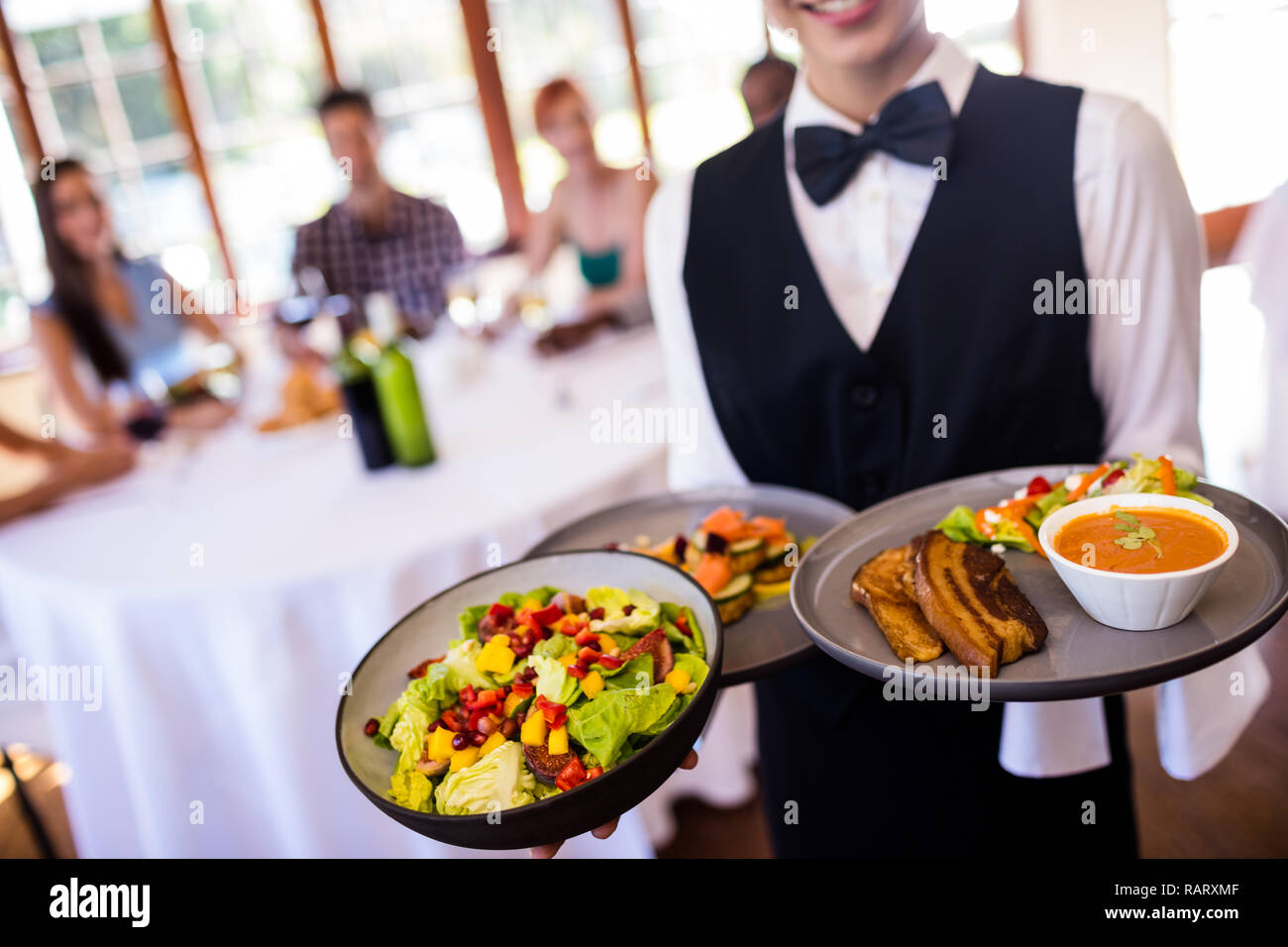 Waitress holding food on plate in restaurant Stock Photo - Alamy