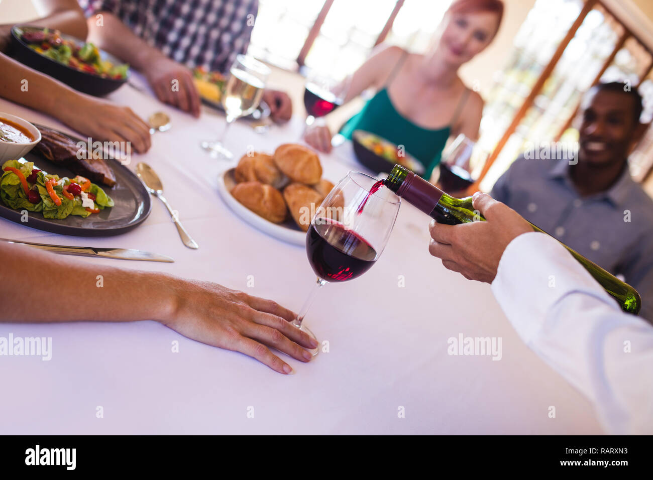 Waitress pouring red wine in wine glass on table Stock Photo - Alamy
