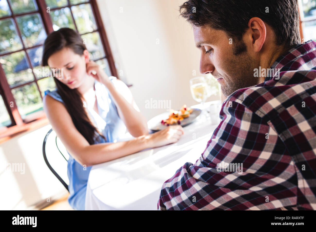 Couple ignoring each other in restaurant Stock Photo - Alamy