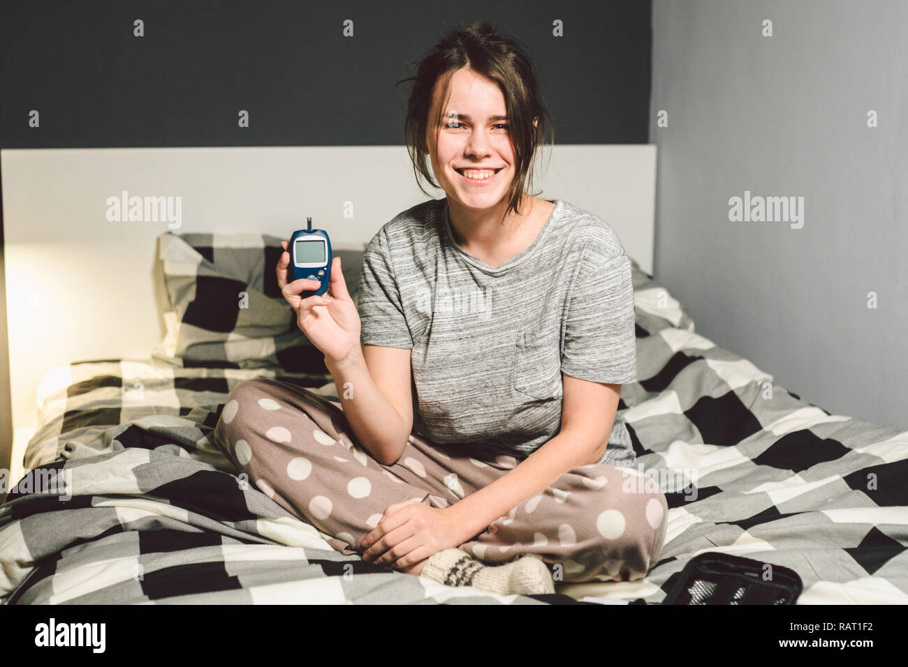 Theme diabetes. young caucasian woman at home in the bedroom on the bed ...