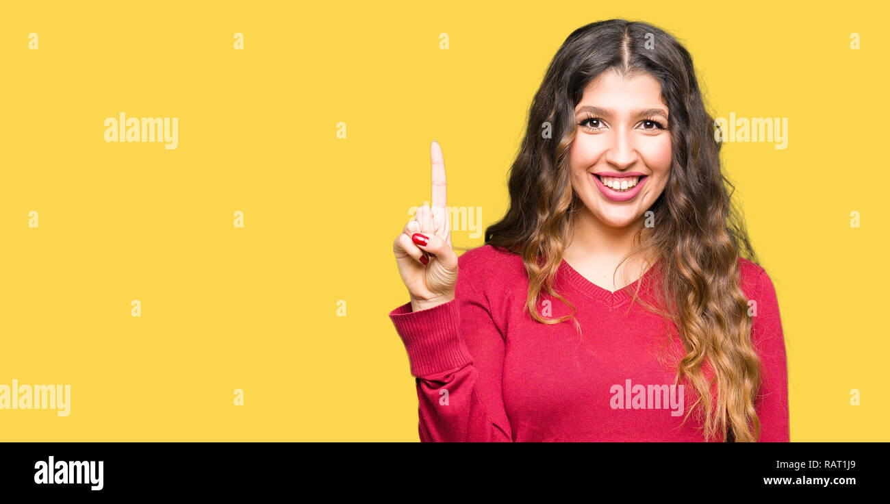 Young beautiful woman wearing red sweater showing and pointing up with ...