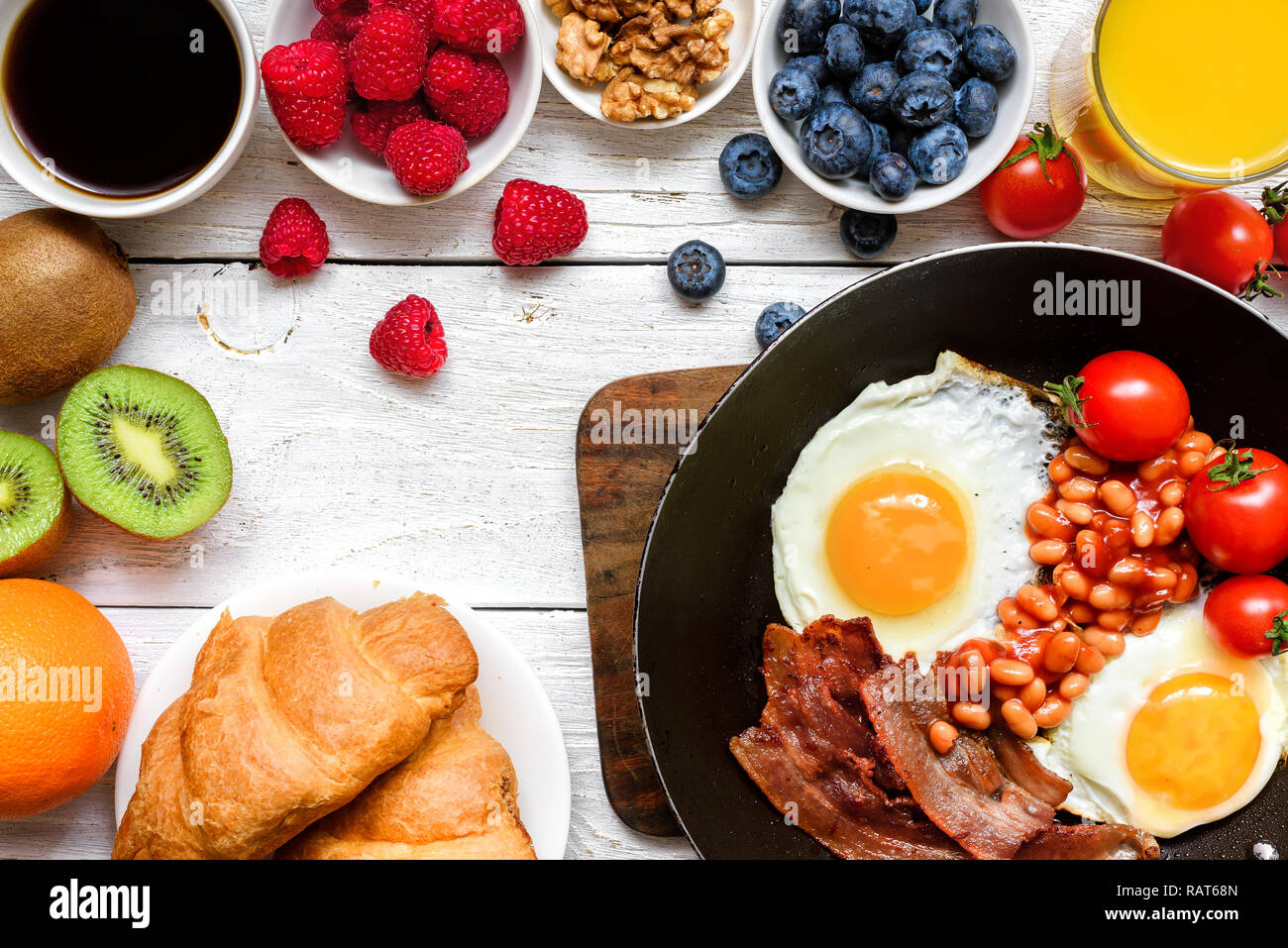 Breakfast including coffee, fried egg ,bacon, beans, croissant, orange ...