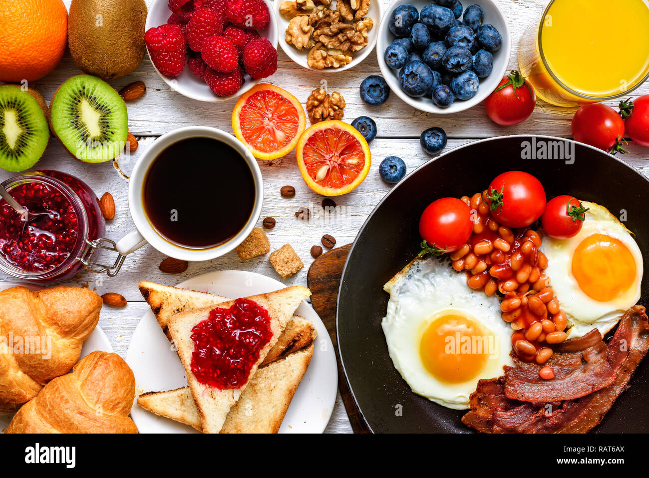 breakfast including coffee, fried egg, bacon, beans, toast, croissant ...