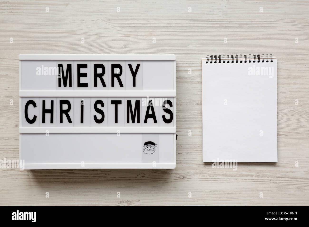 'Merry Christmas' words on lightbox, blank notepad over white wooden ...