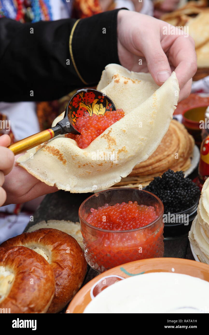 Hand puts caviar on pancake Stock Photo - Alamy