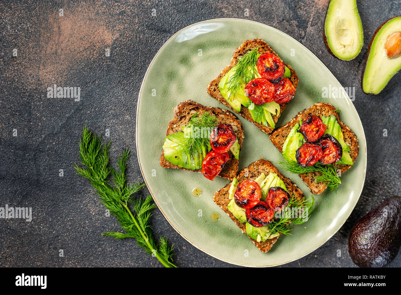 Avocado toasts with roasted tomatoes in a plate Stock Photo - Alamy