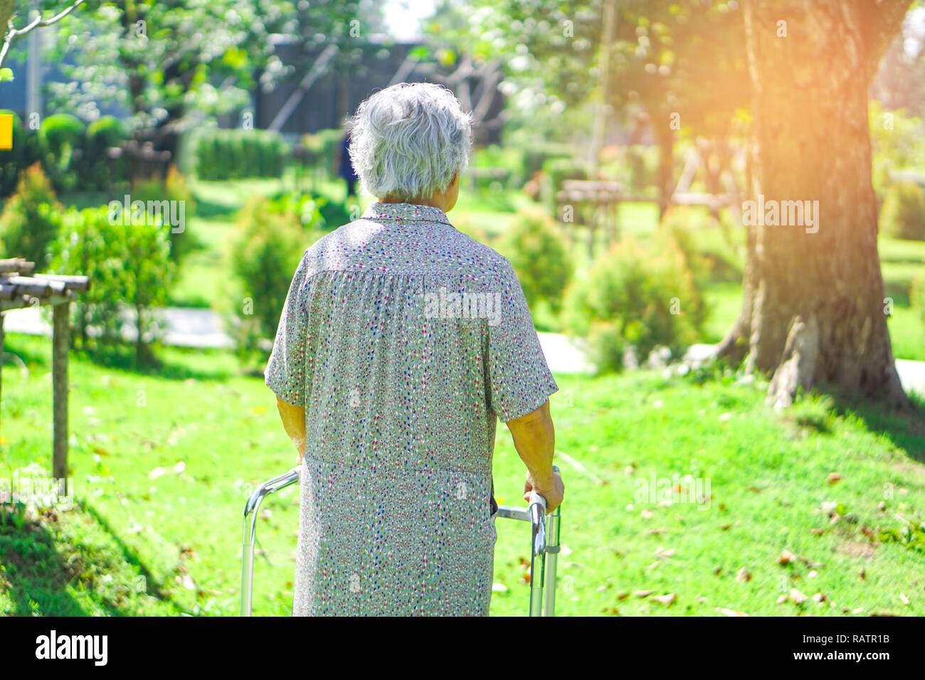 Asian senior or elderly old lady woman patient walk with walker in park ...