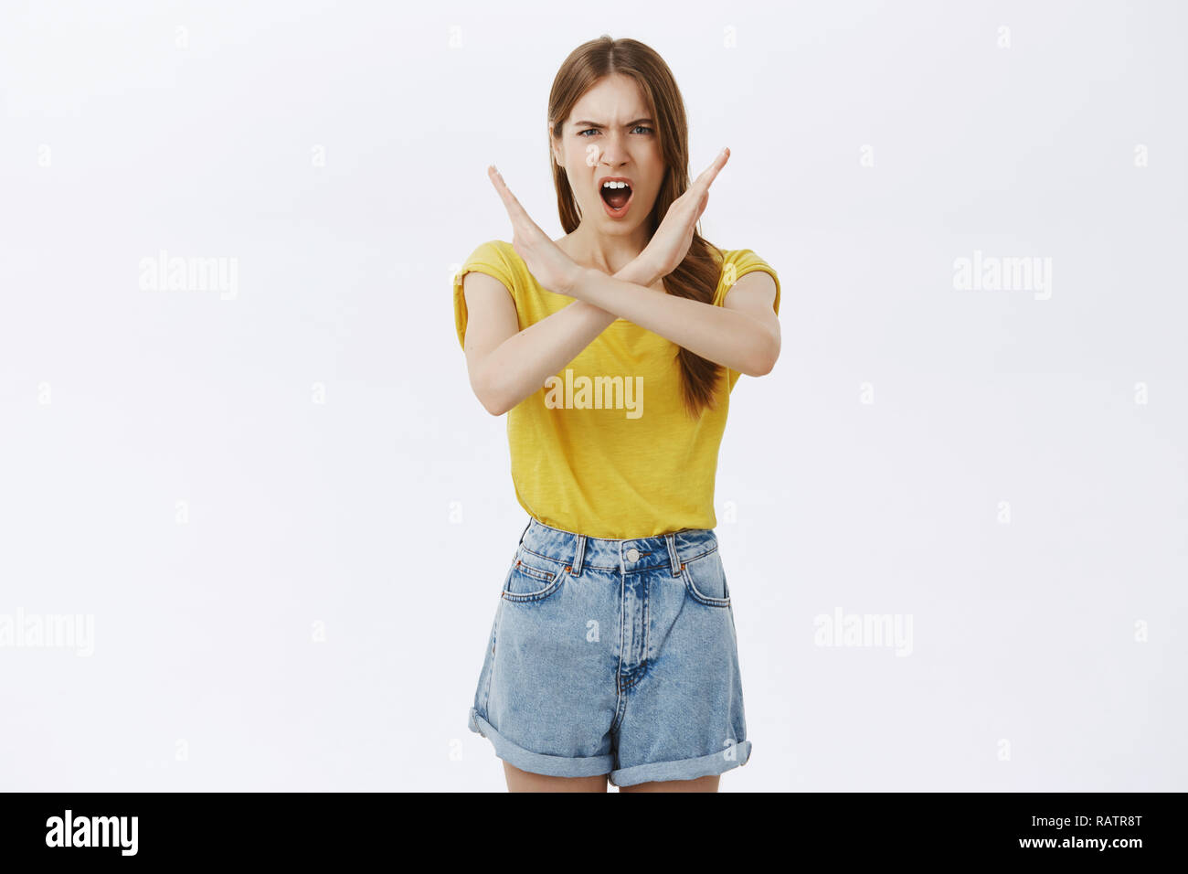 Angry displeased young slender european female in yellow t-shirt and ...