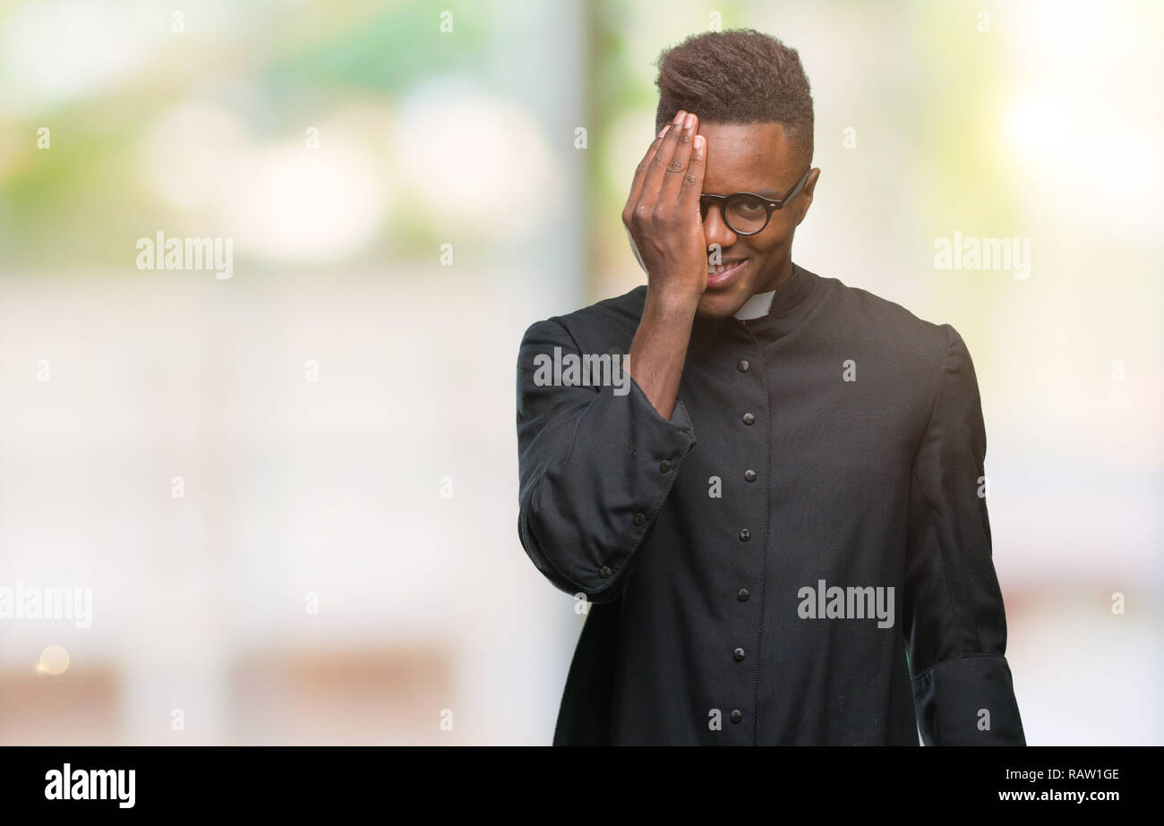Young african american priest man over isolated background covering one ...