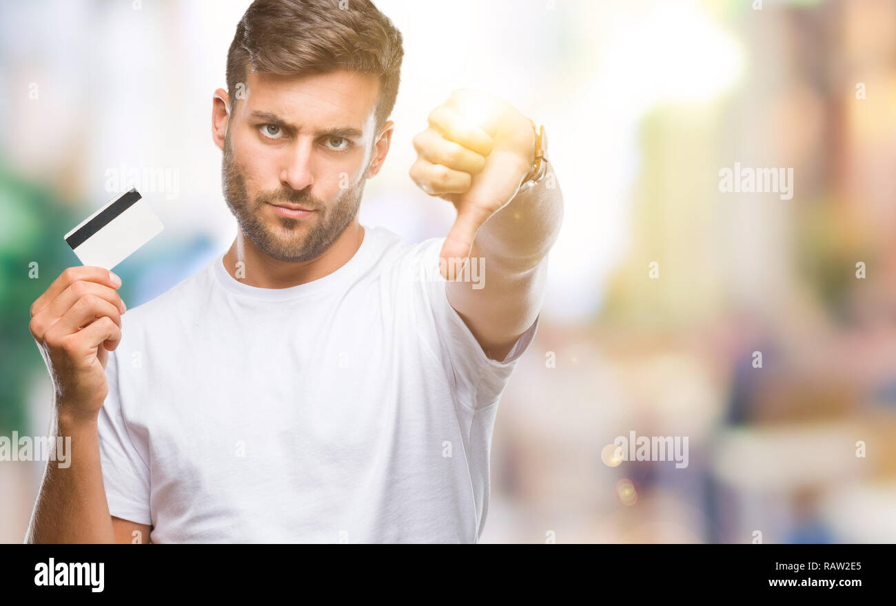 Young handsome man holding credit card over isolated background with ...