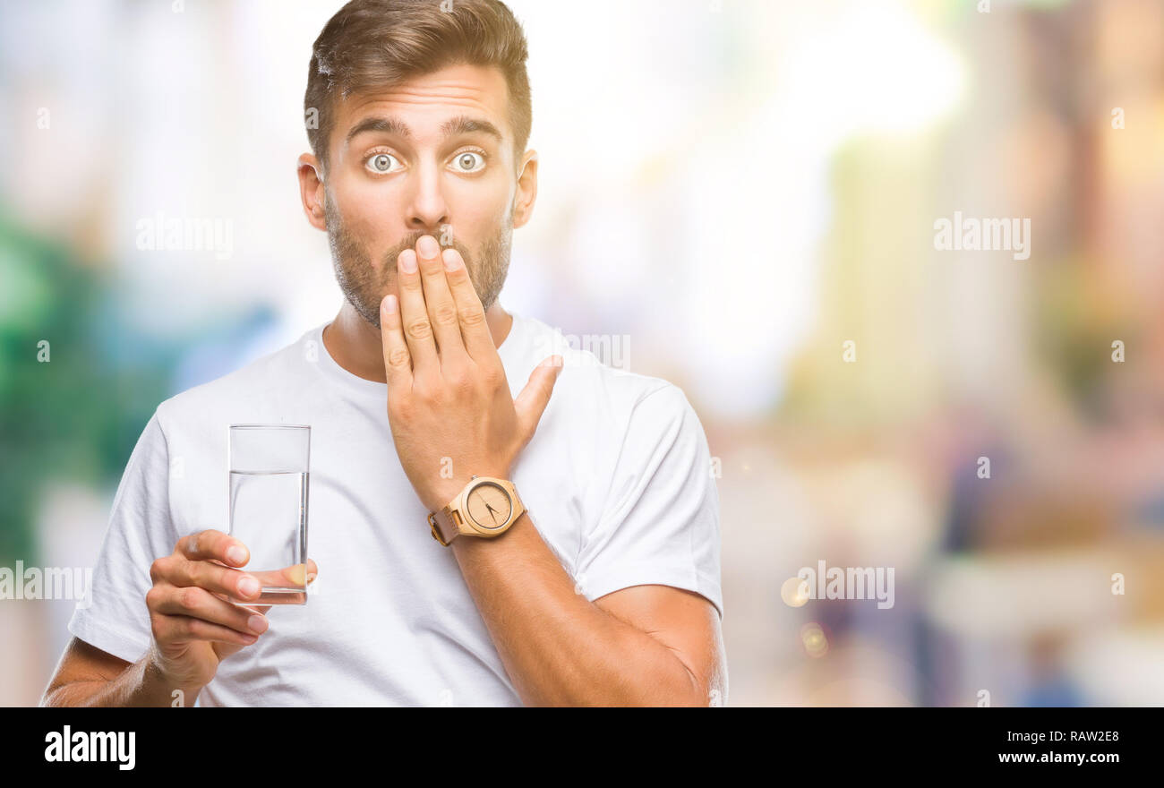 Young handsome man drinking glass of water over isolated background ...