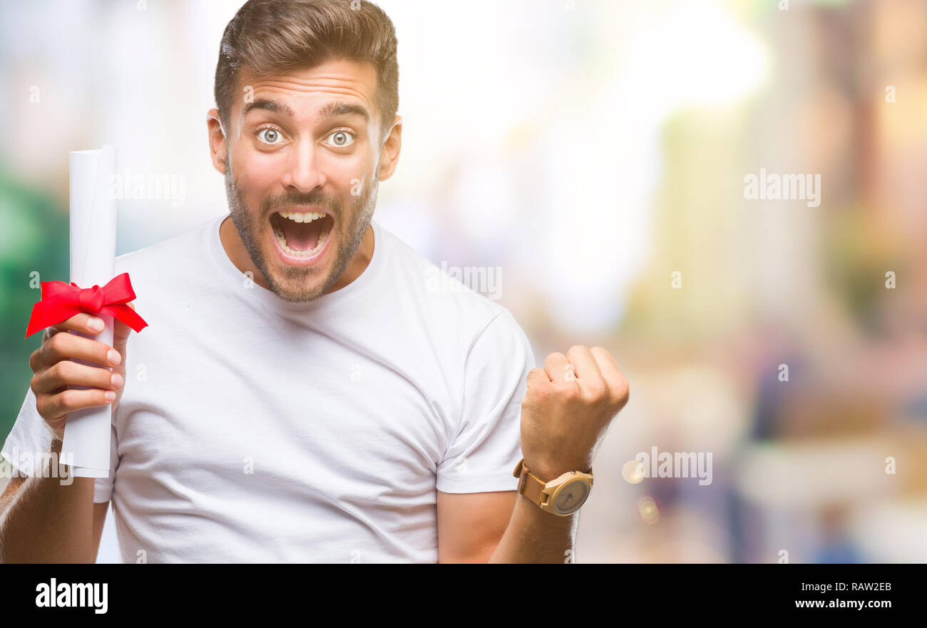 Young handsome man holding degree over isolated background screaming ...