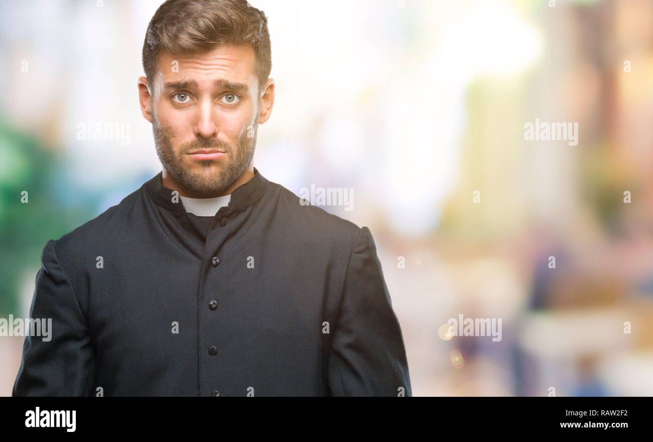 Young catholic christian priest man over isolated background depressed ...