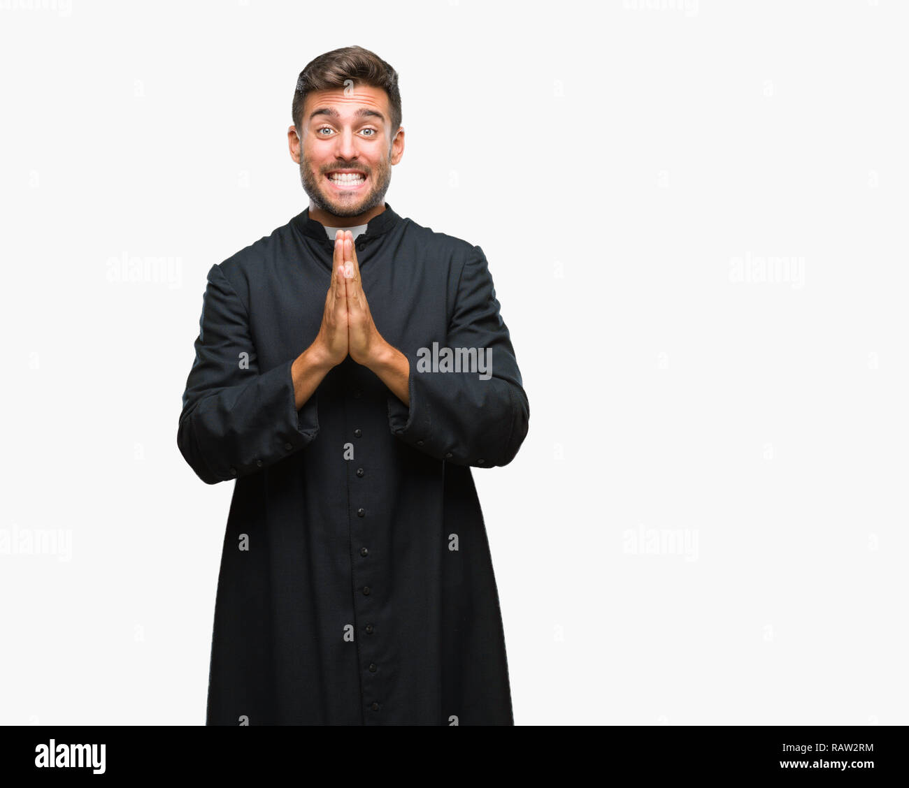Young catholic christian priest man over isolated background praying ...