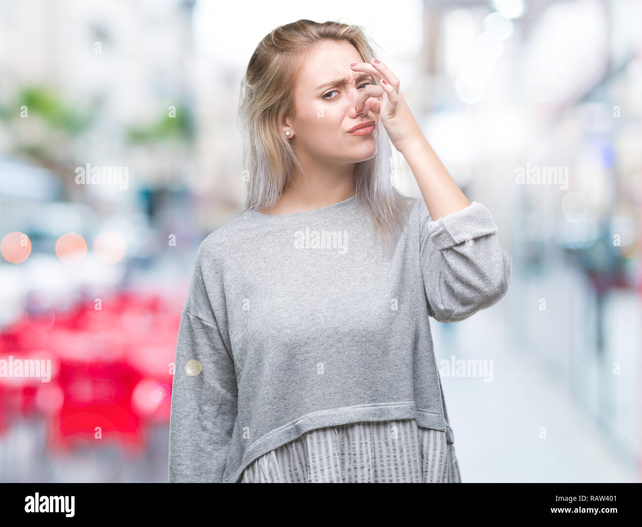 Young blonde woman over isolated background smelling something stinky ...