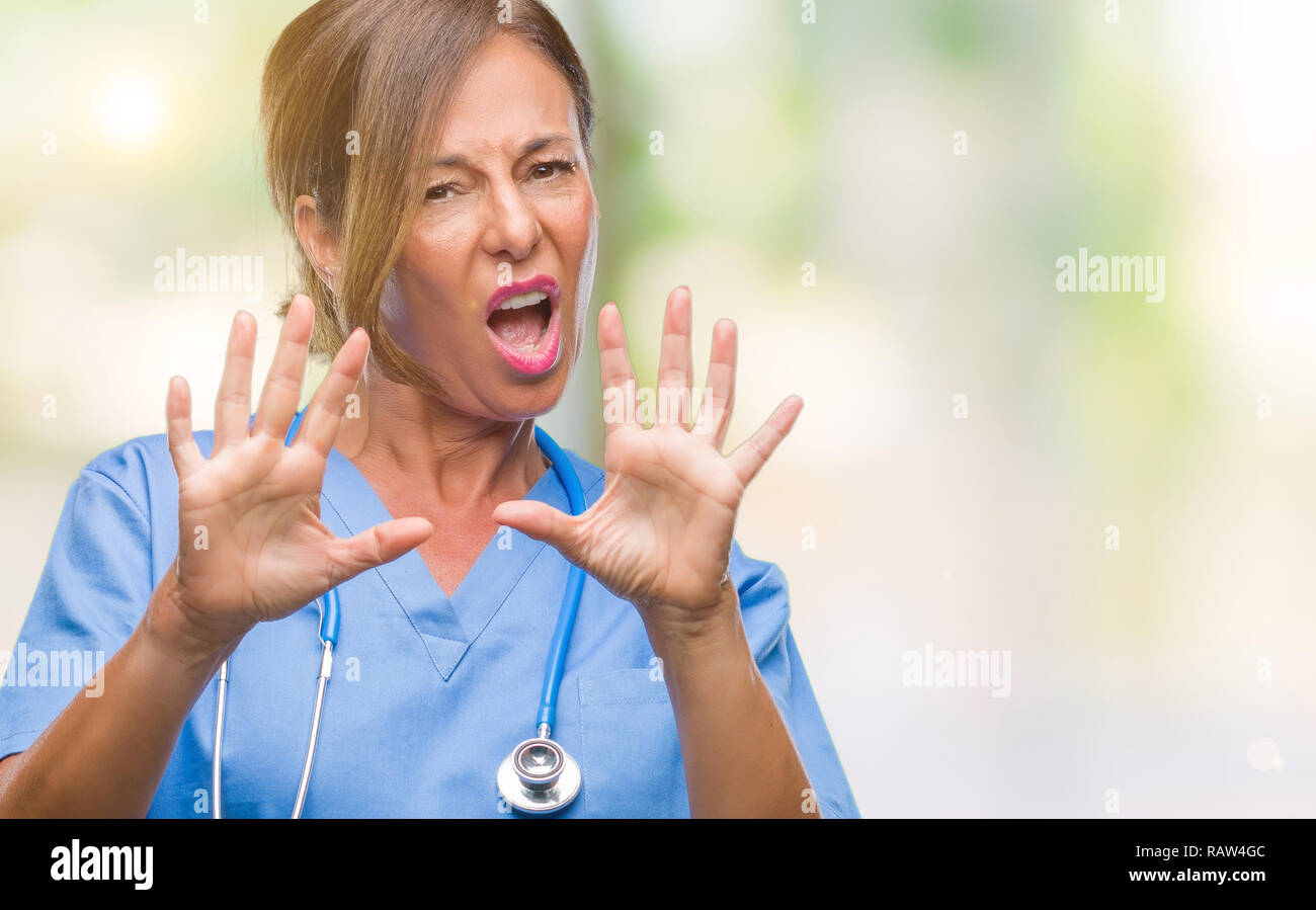 Middle age senior nurse doctor woman over isolated background afraid ...