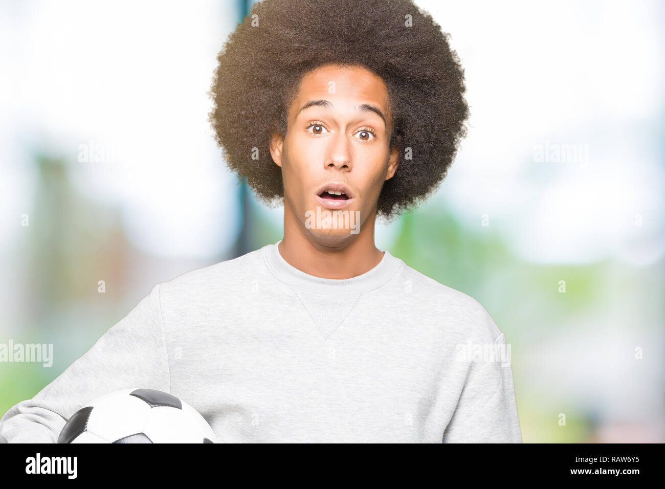 Young african american man with afro hair holding soccer football ball ...
