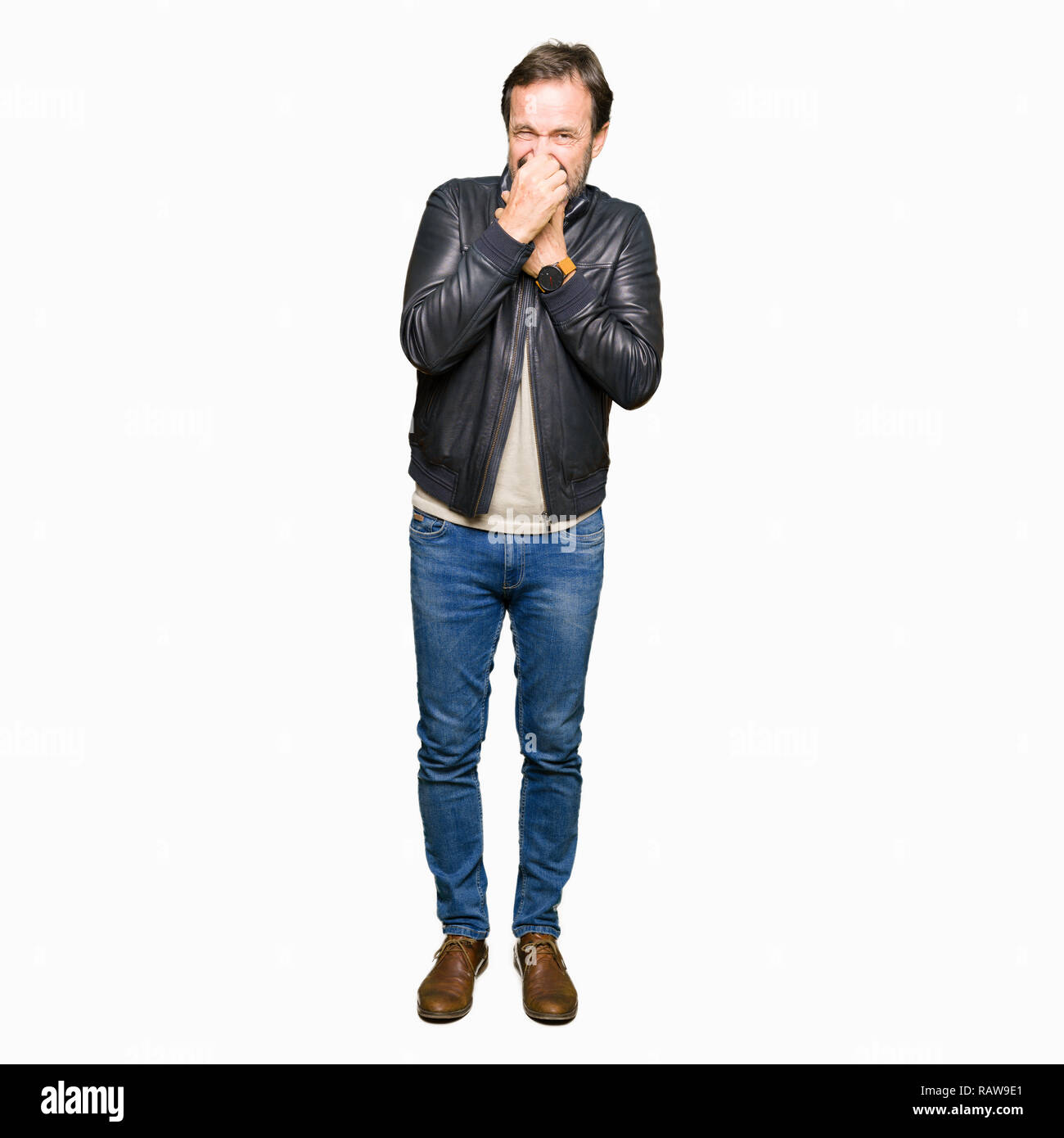 Middle age handsome man wearing black leather jacket smelling something ...