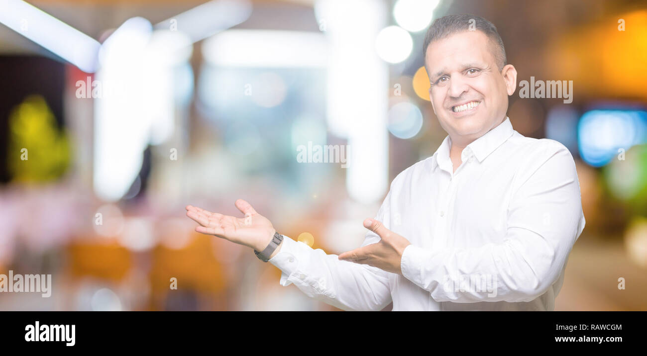 Middle age arab elegant man over isolated background Inviting to enter ...