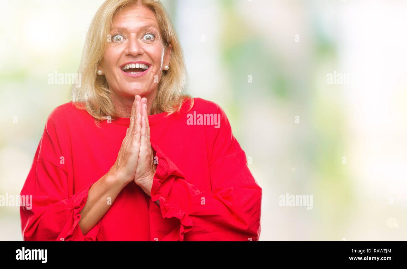 Middle age blonde woman over isolated background begging and praying with hands together with ...