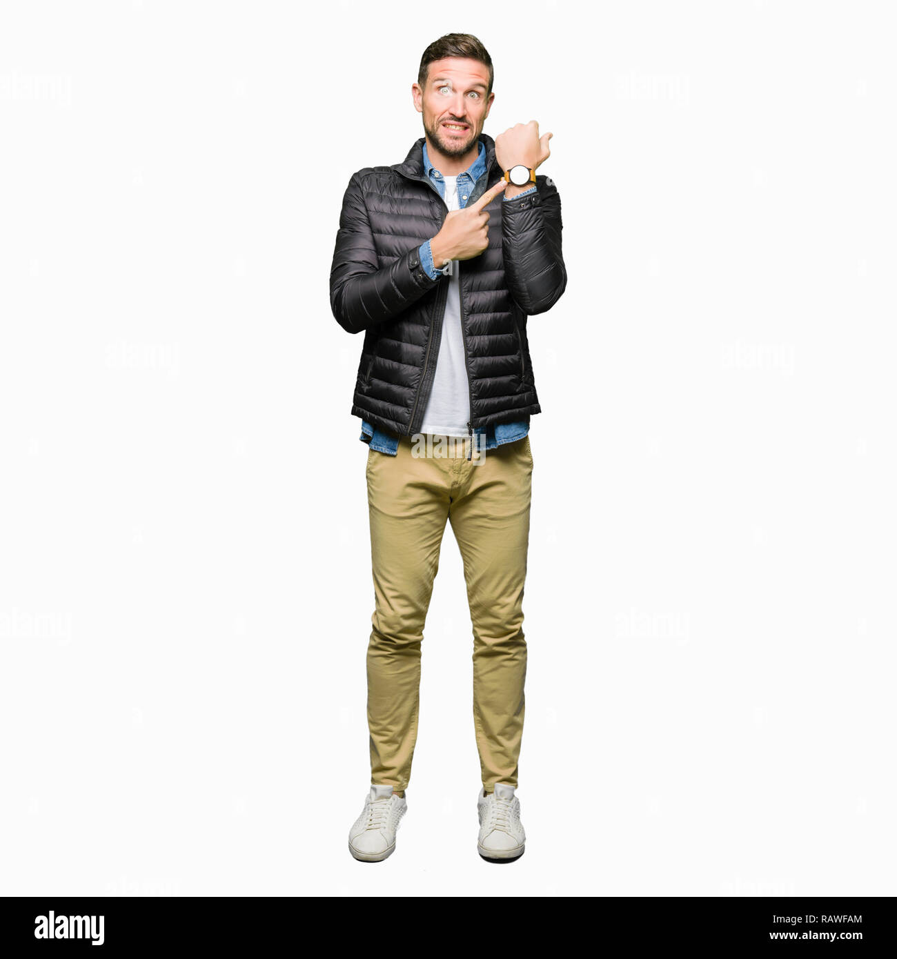 Handsome man wearing winter coat In hurry pointing to watch time ...