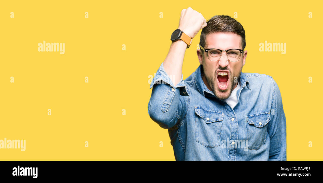 Handsome man wearing glasses angry and mad raising fist frustrated and ...
