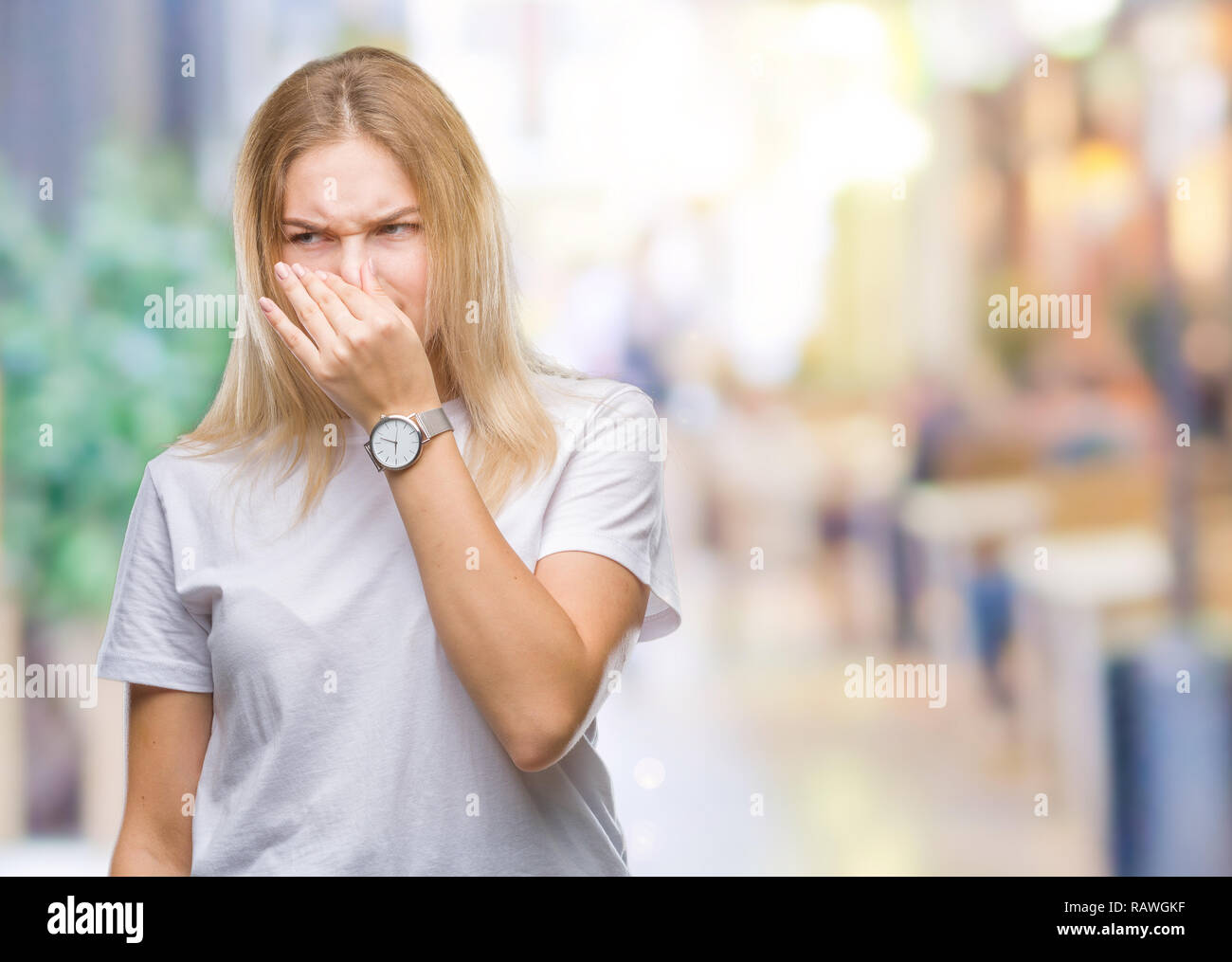 Young caucasian woman over isolated background smelling something ...