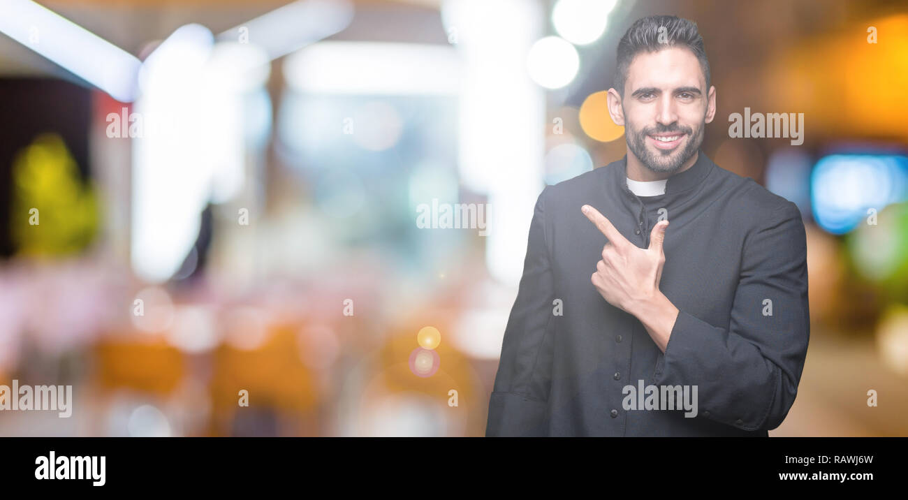 Young Christian priest over isolated background cheerful with a smile ...