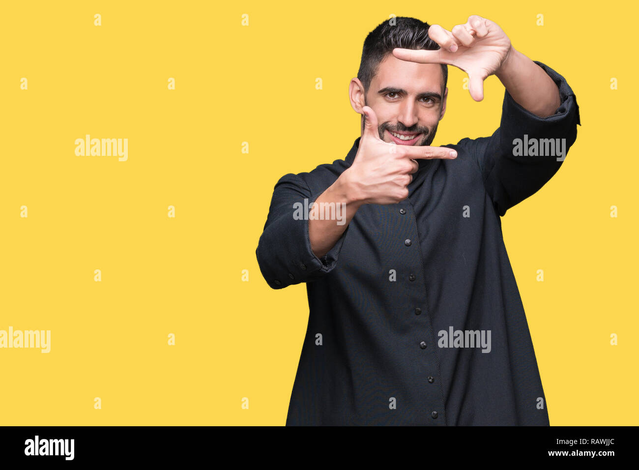 Young Christian priest over isolated background smiling making frame ...