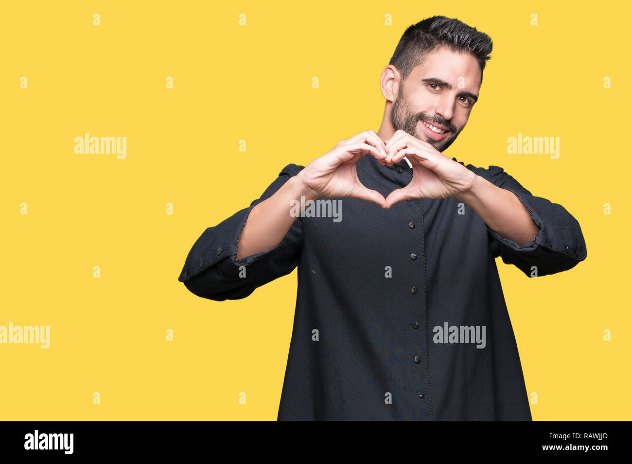 Young Christian priest over isolated background smiling in love showing ...