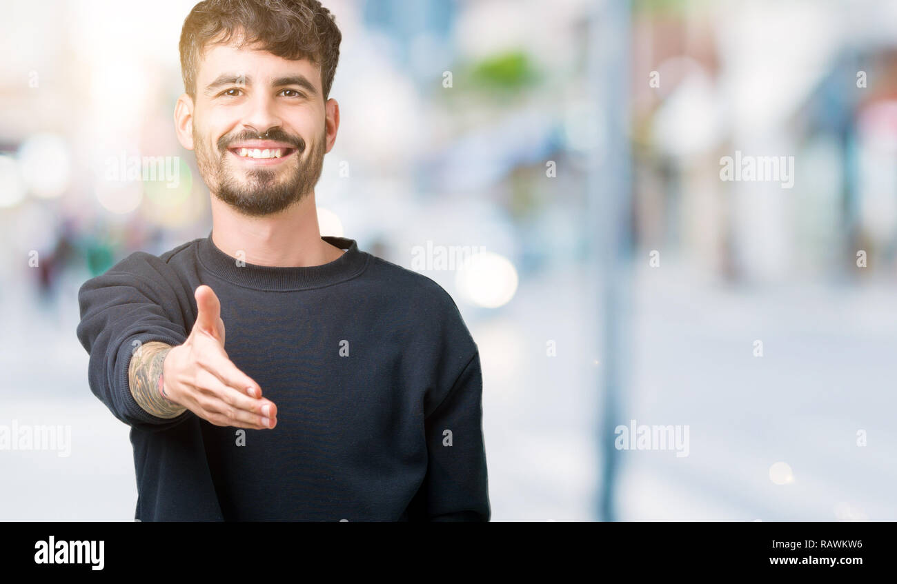 Young handsome man over isolated background smiling friendly offering ...
