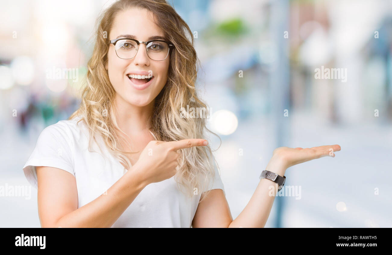 Beautiful young blonde woman wearing glasses over isolated background ...