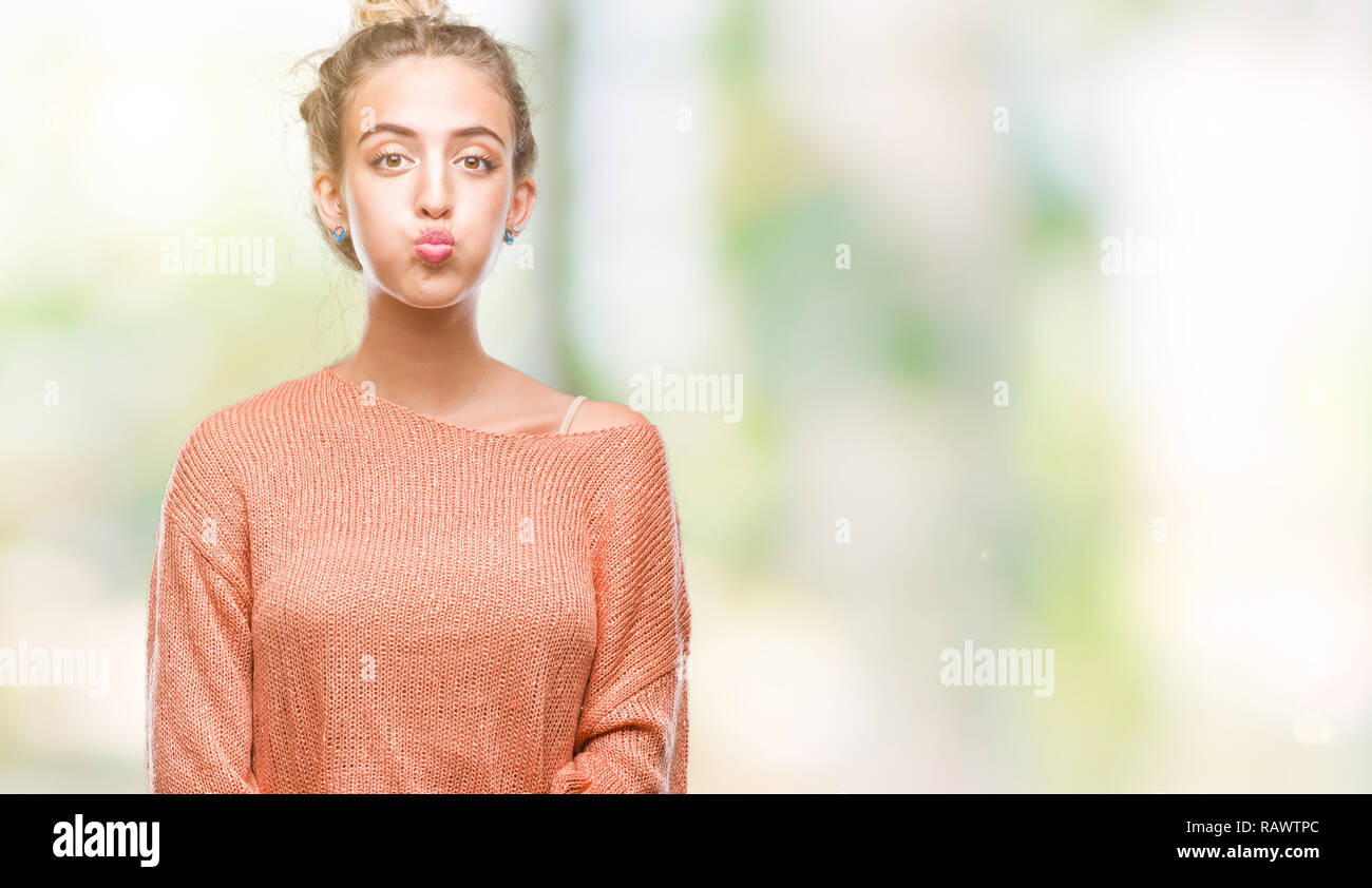 Beautiful young blonde woman over isolated background puffing cheeks ...