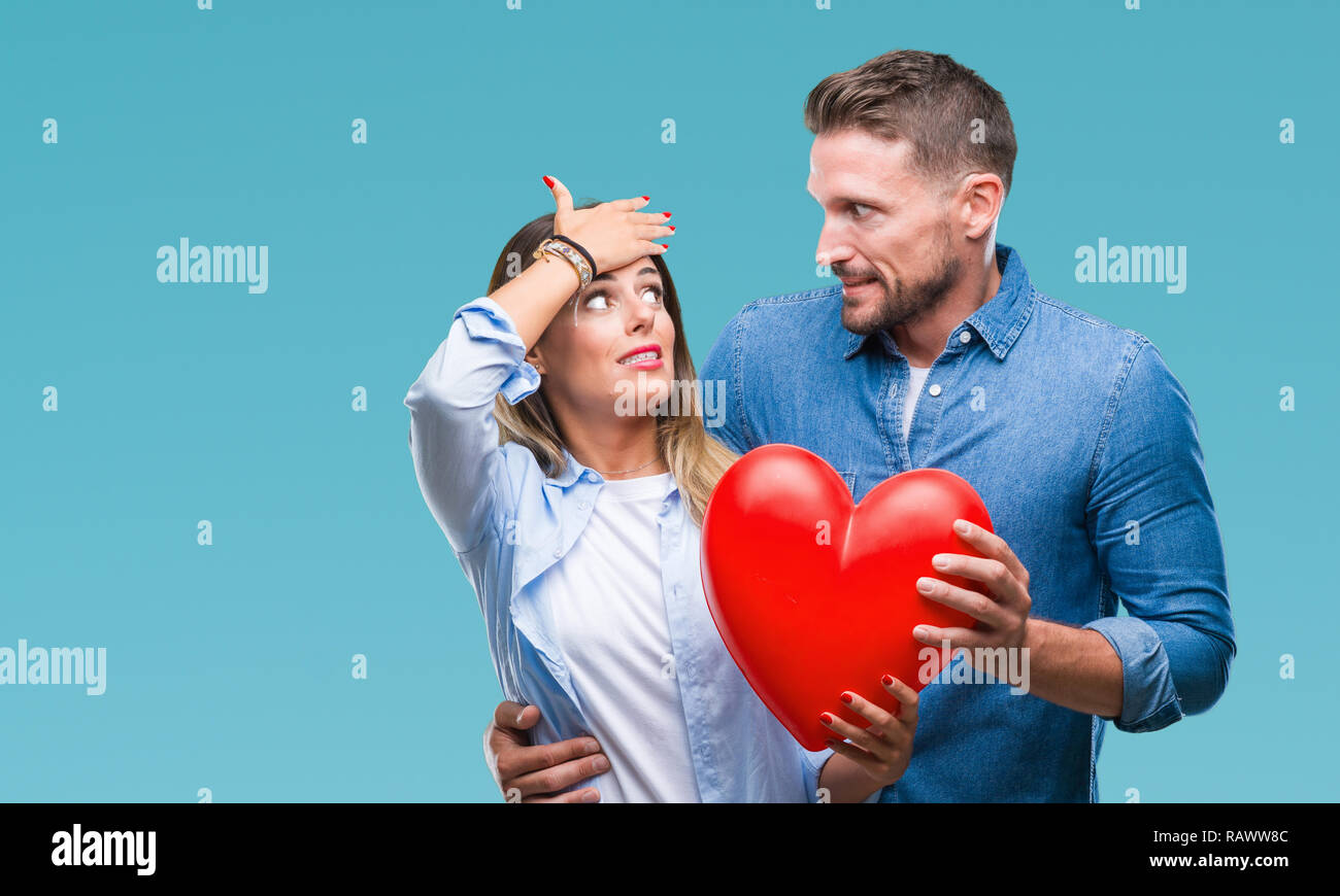 Young couple in love holding red heart over isolated background ...