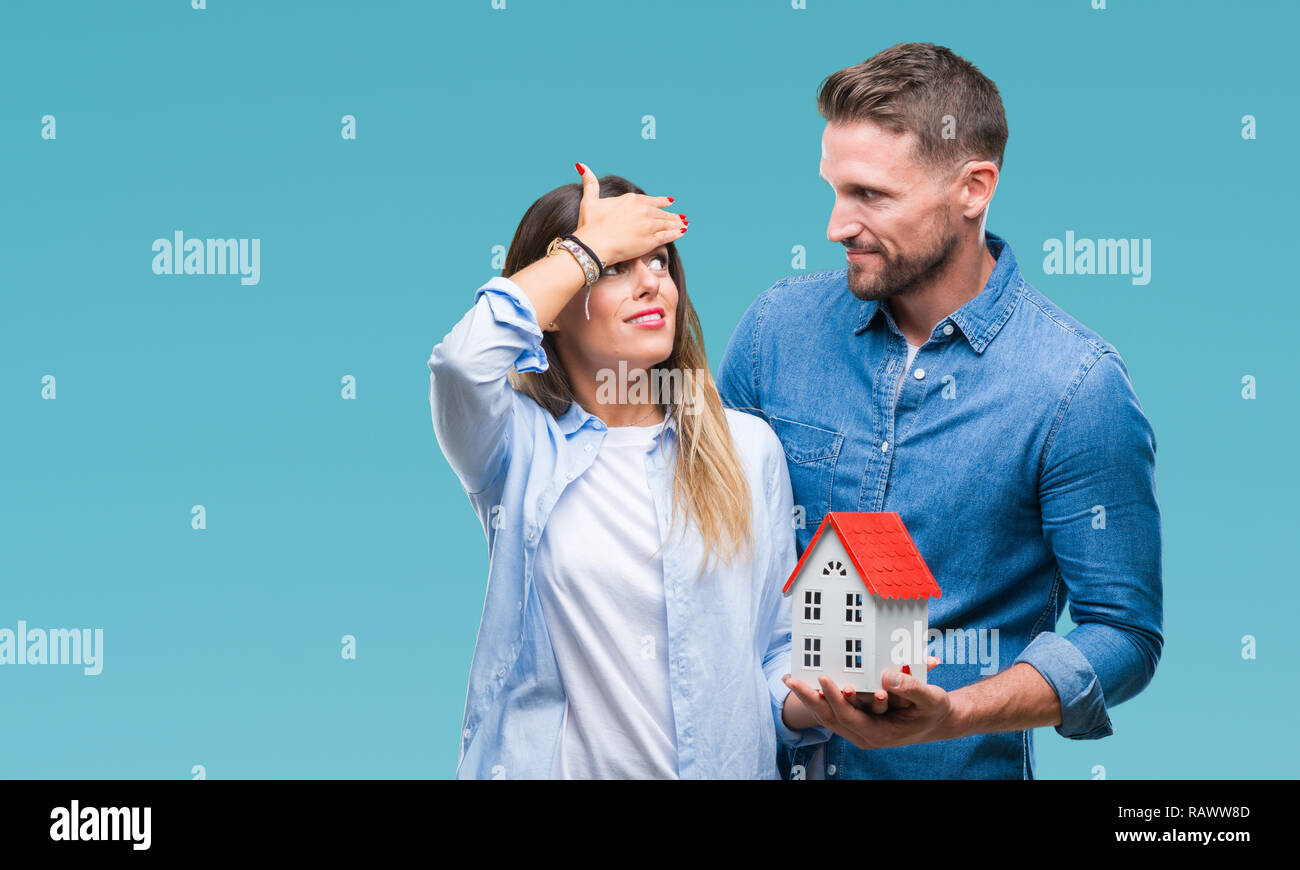 Young couple in love holding house over isolated background stressed ...