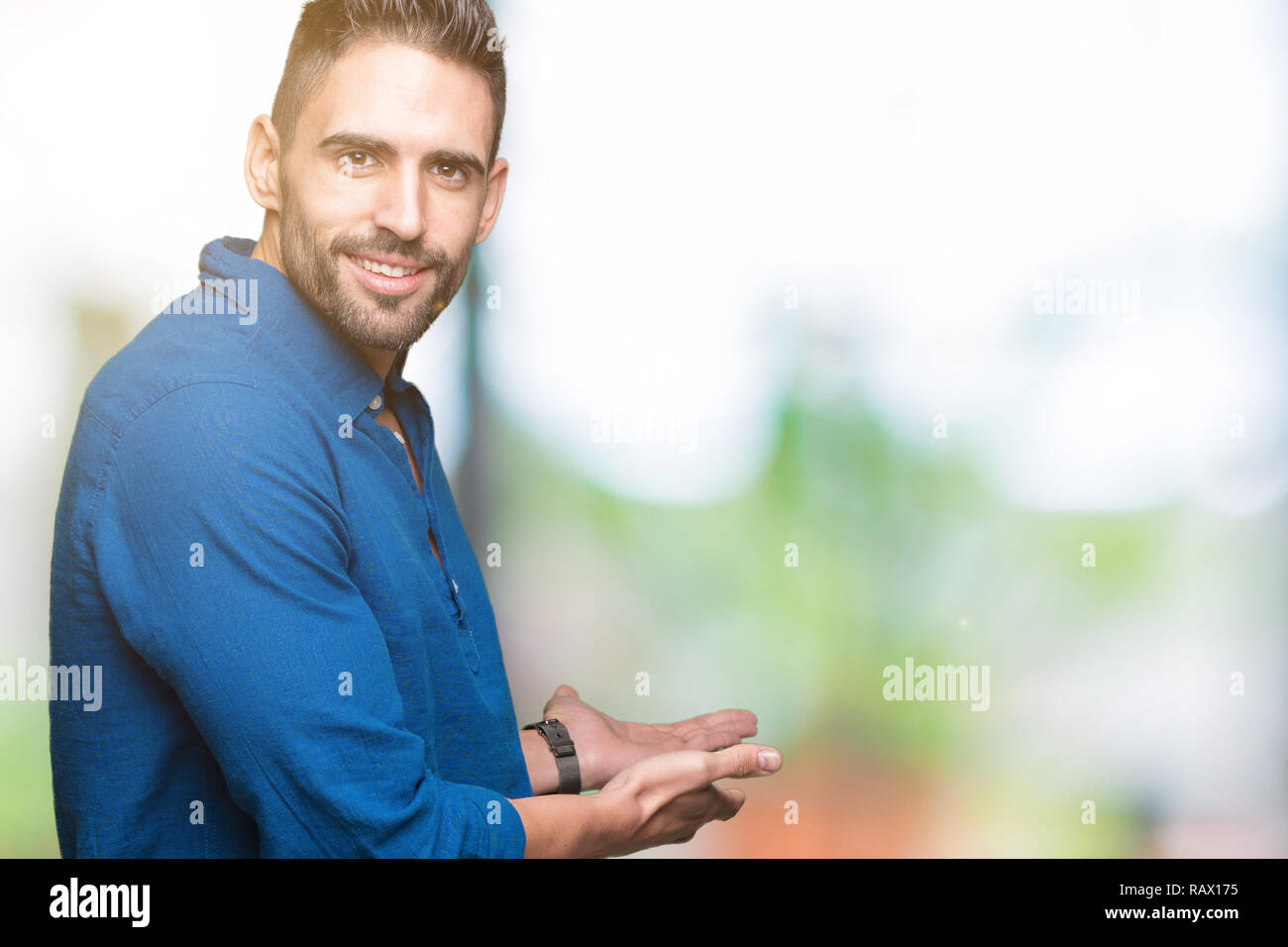 Young handsome man over isolated background Inviting to enter smiling ...