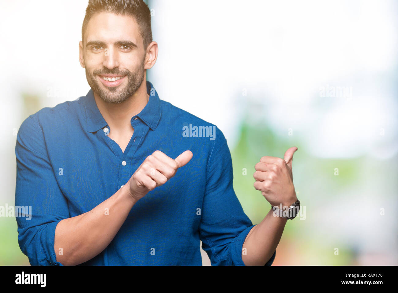 Young handsome man over isolated background Pointing to the back behind ...