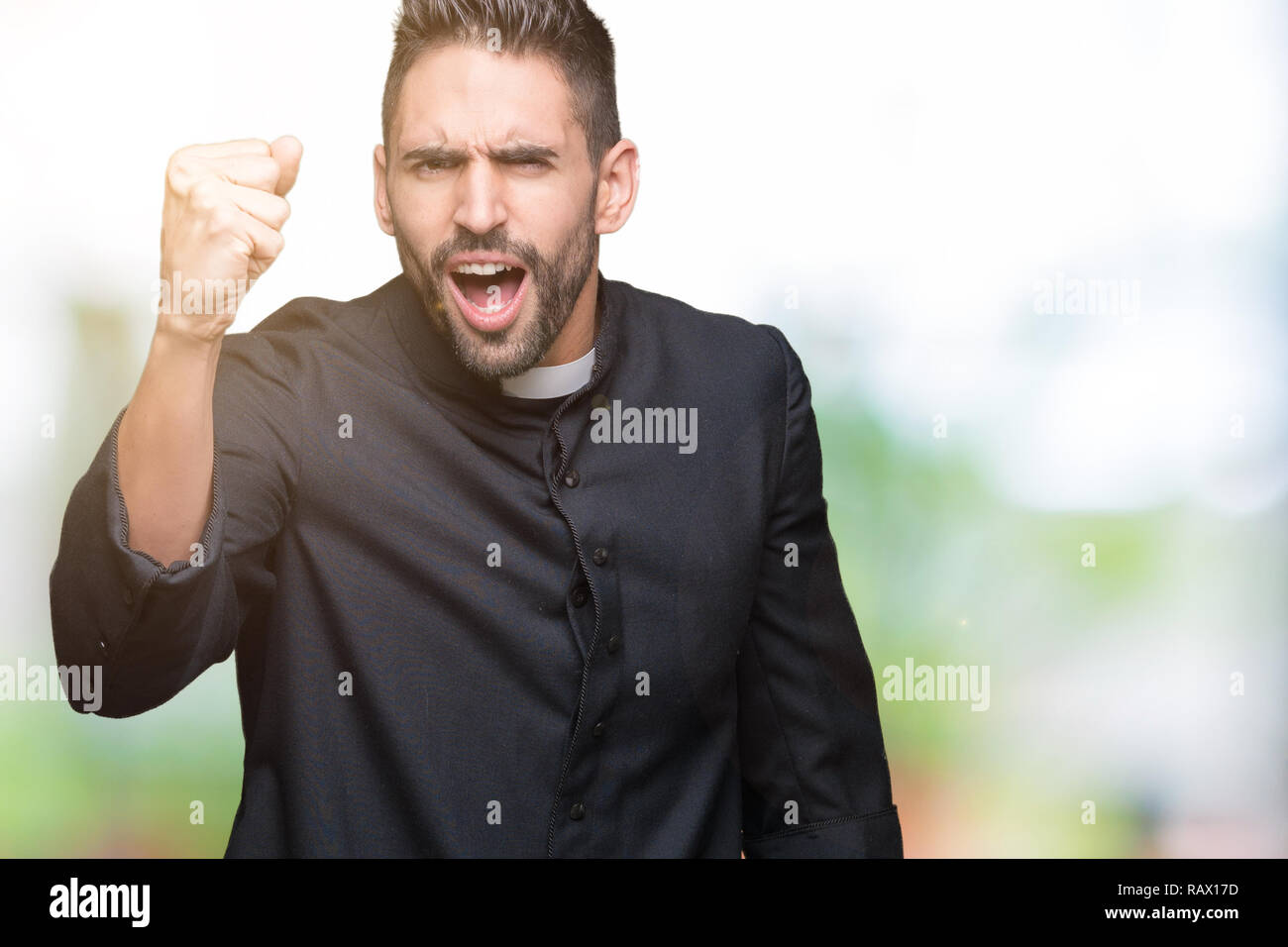 Young Christian priest over isolated background angry and mad raising ...