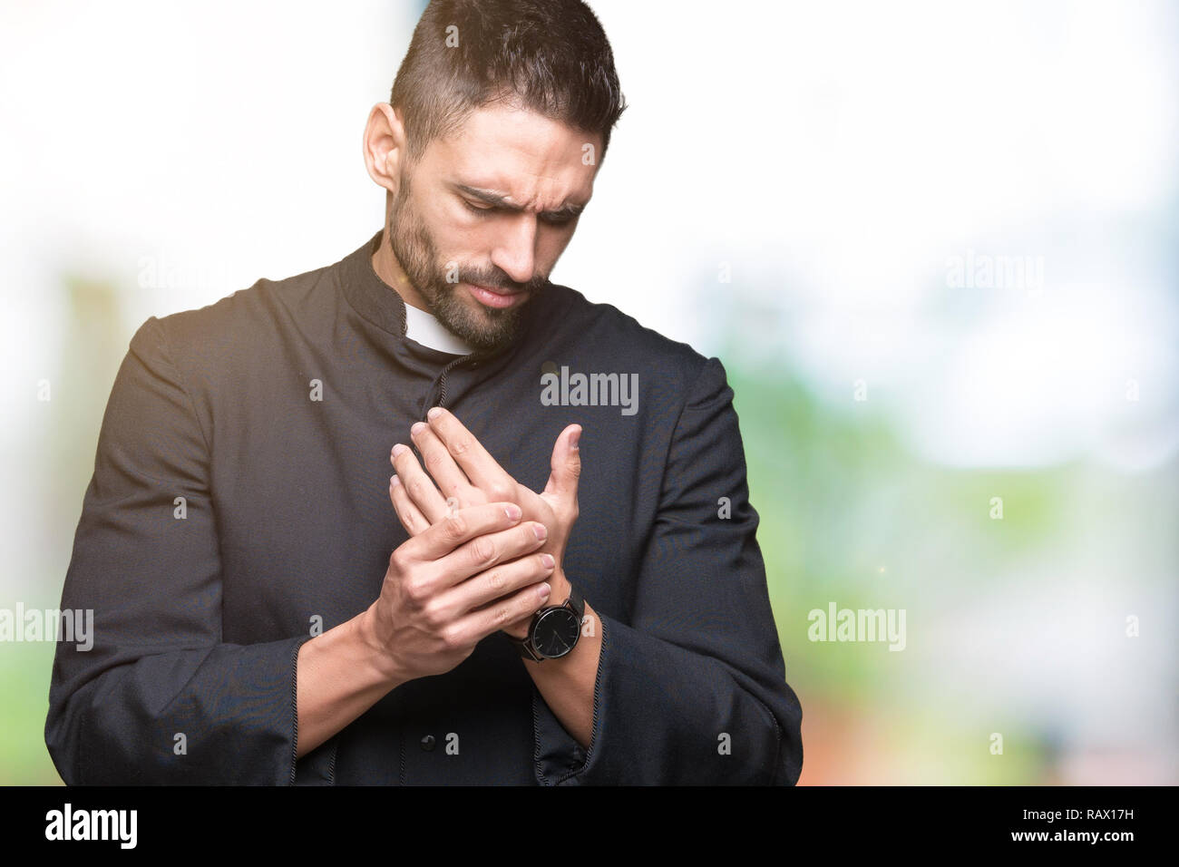 Young Christian priest over isolated background Suffering pain on hands ...